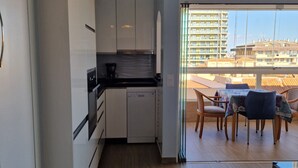 Uma cozinha moderna com armários brancos, máquina de lavar louça e uma área de jantar com mesa e cadeiras.