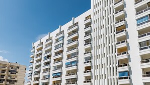 Um edifício de vários andares com varandas, céu claro e design arquitetônico moderno.