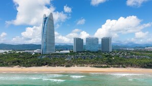 Uma região costeira com edifícios modernos altos, uma praia e montanhas ao fundo.