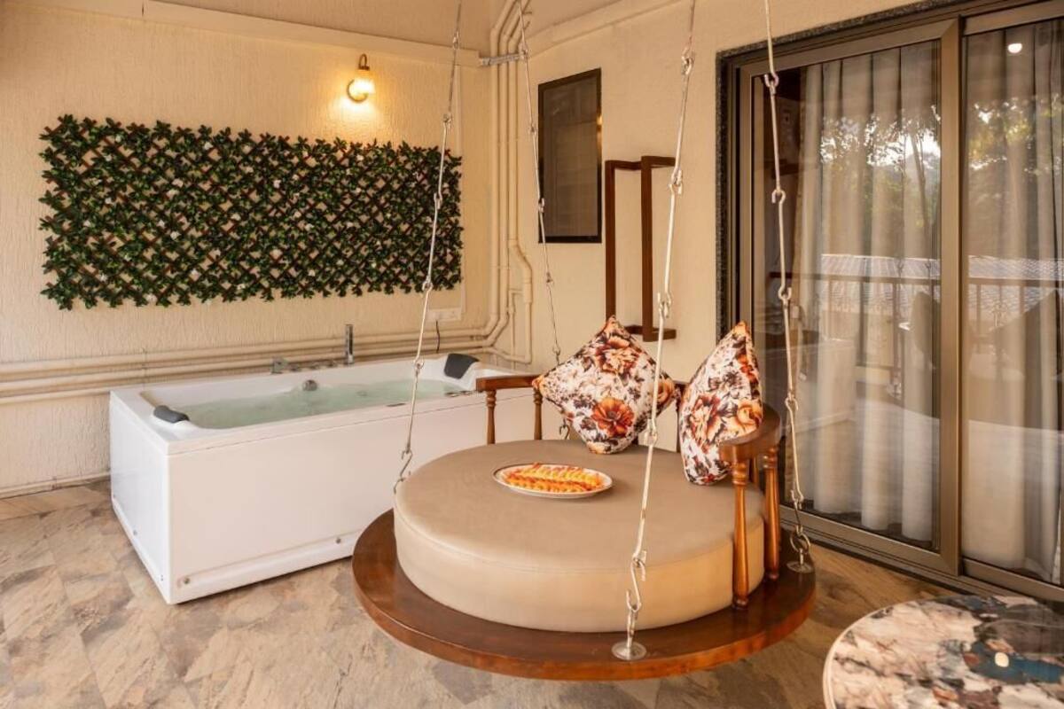 Quarto com cadeira de balanço, banheira e painel decorativo fixado na parede.