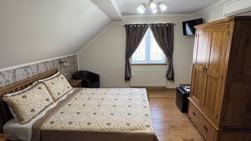 Quarto com cama, guarda-roupa de madeira e janela com cortinas.