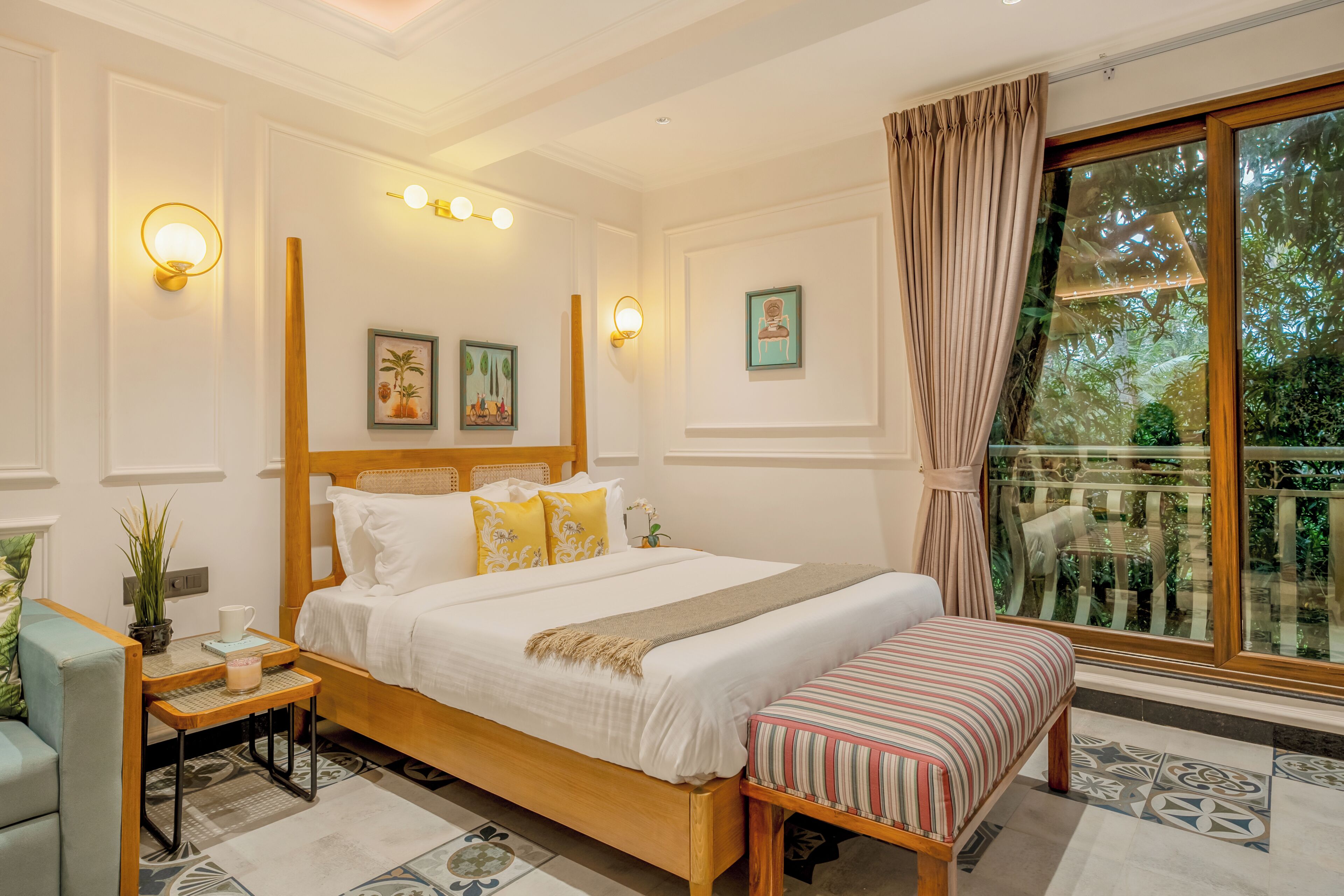 Quarto com cama grande, mesas de cabeceira, um banco, janela com vista e luminárias fixadas na parede.