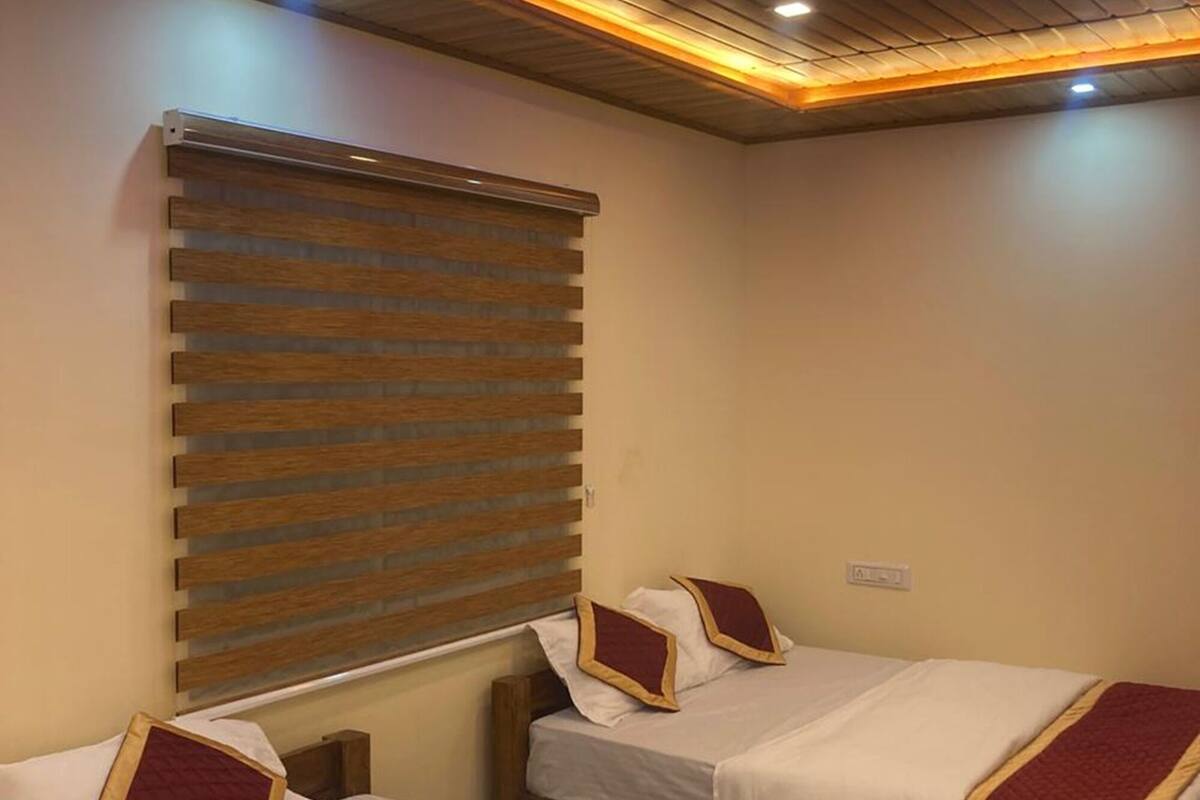 Quarto de hotel com duas camas, cabeceiras de madeira, ventilador de teto e janela com persianas.