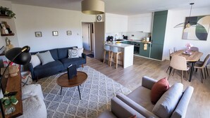 Uma sala de estar moderna com um sofá, mesa de centro e um espaço de jantar com cadeiras e uma mesa.