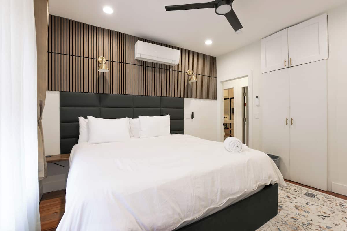 Quarto com cama, ventoinha no teto, ar condicionado e guarda-roupa.