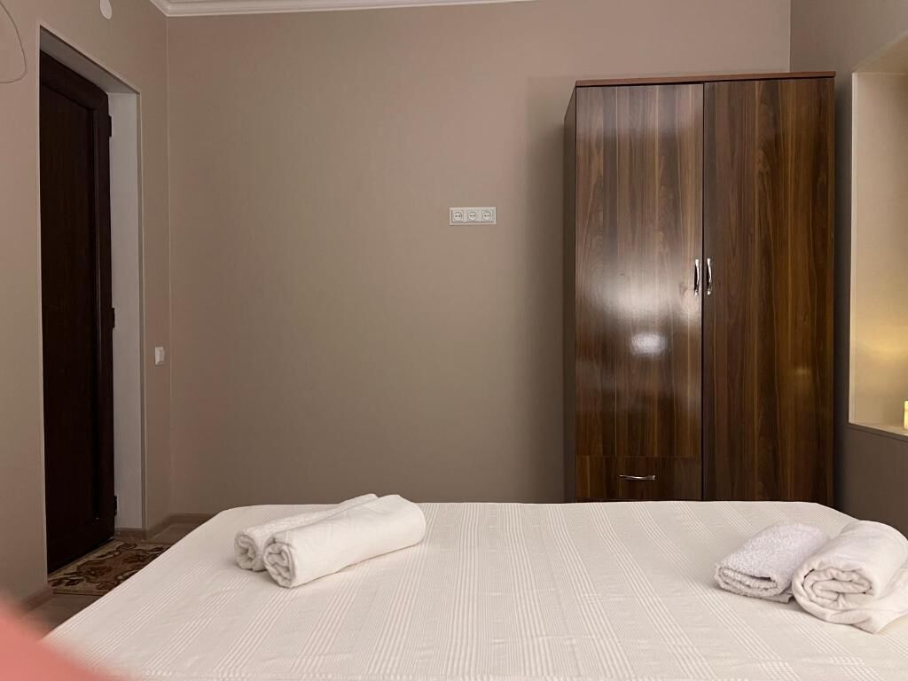 Quarto de hotel com cama, duas toalhas enroladas, guarda-roupa e uma porta.