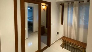 Quarto com porta de correr em madeira, um banco e vista pela janela com cortinas.