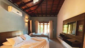 Quarto de hotel com duas camas, televisão, prateleira embutida e janela com cortinas.