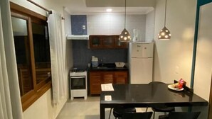 Uma cozinha compacta com mesa de jantar, cadeiras, geladeira e luminárias pendentes.