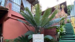 Um pátio com uma estátua, degraus e um edifício com parede vermelha e varanda.