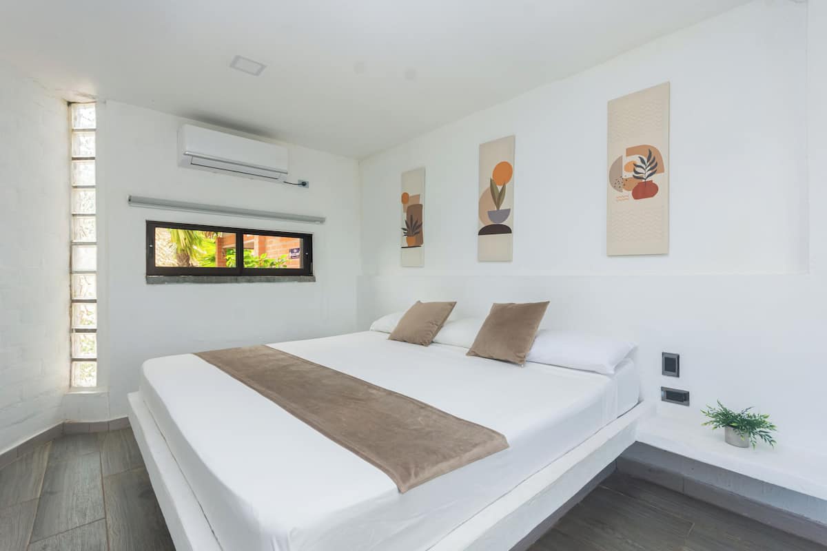 Quarto moderno com uma cama grande, uma janela e quadros nas paredes.
