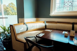 Uma área de estar em canto com uma mesa de madeira, cadeiras e um banco.