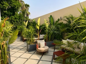 Jardim no terraço com áreas de estar, plantas em vasos e piso de azulejos.