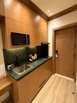 Cozinha compacta com micro-ondas embutido, máquina de café e pia.