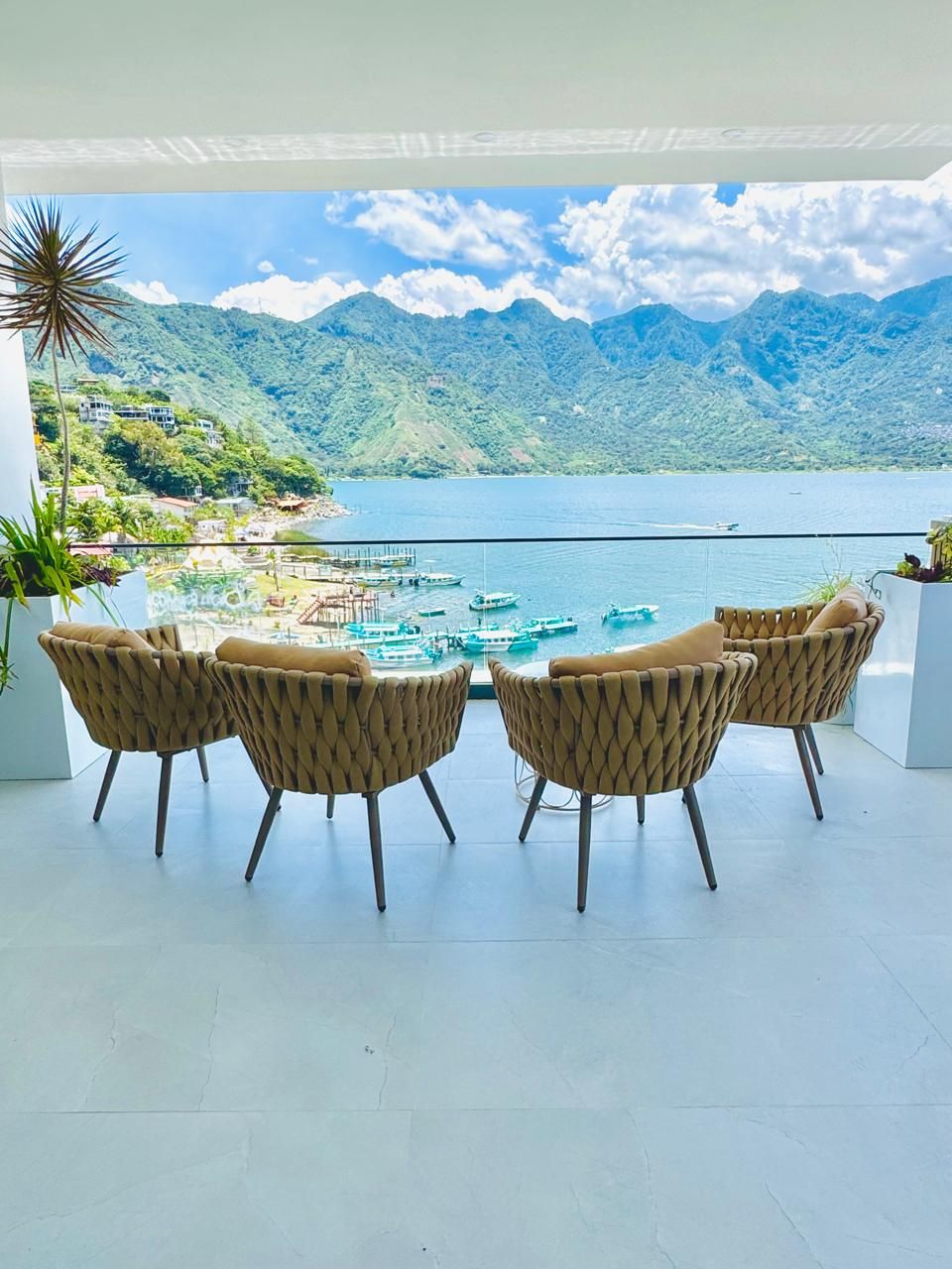 Varanda com cadeiras de vime e vista para um lago com barcos.
