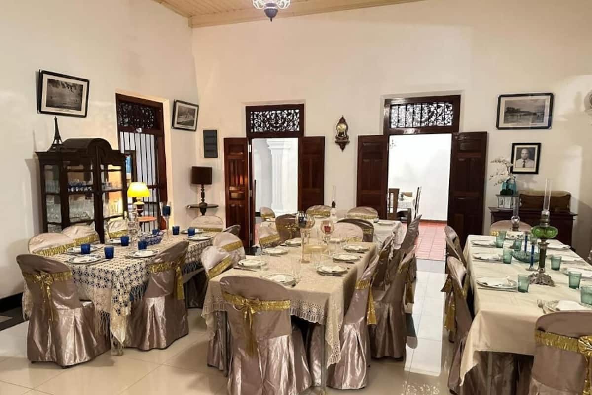 Uma sala de jantar com várias mesas preparadas para uma refeição, cada uma com cadeiras e toalhas de mesa.