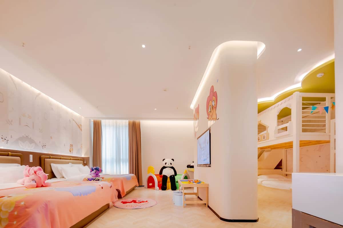 Quarto infantil com duas camas, um espaço para brincar e uma cama beliche.