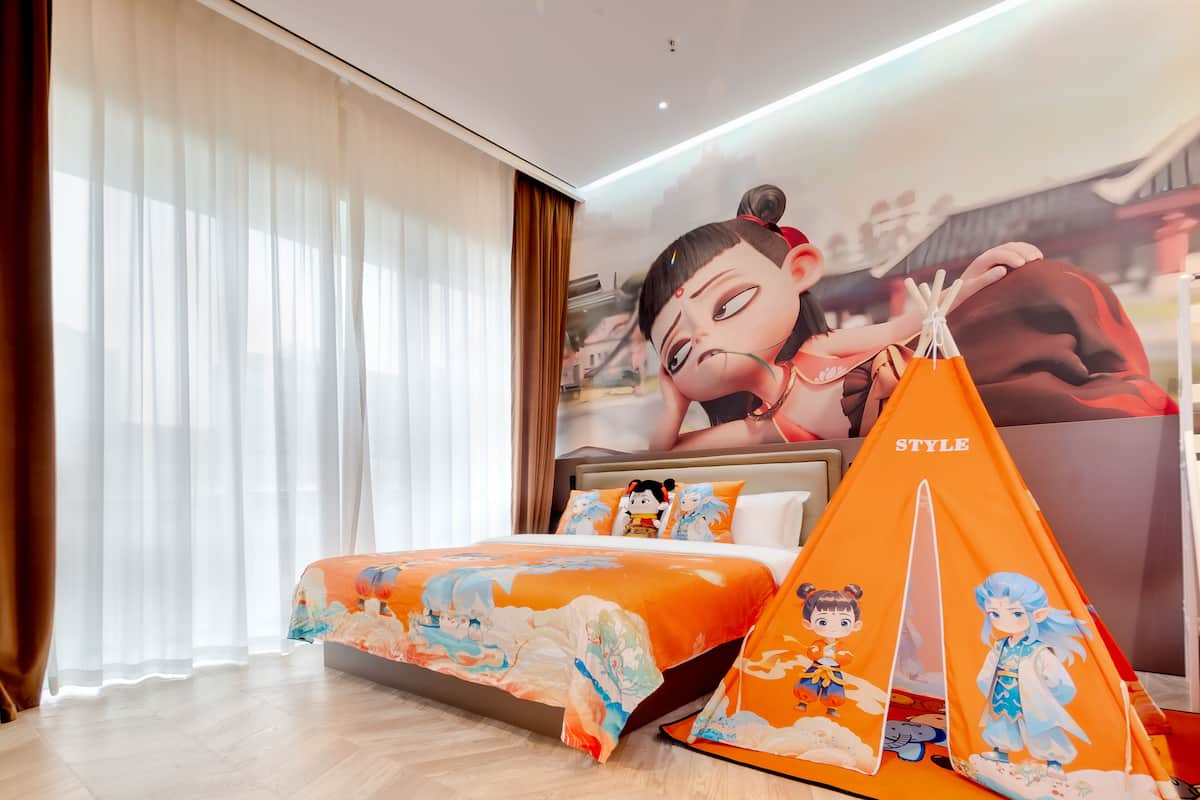 Quarto de hotel com cama, janela com cortinas, painel na parede e decoração semelhante a uma tenda.