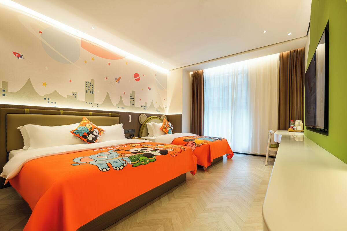 Quarto de hotel com uma cama, duas mesas de cabeceira, uma televisão e uma janela com cortinas.