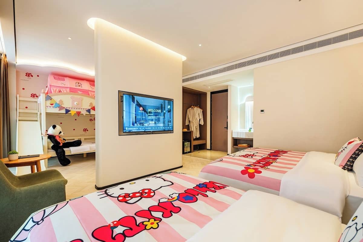 Quarto de hotel com duas camas, uma televisão, uma escrivaninha e um guarda-roupa.