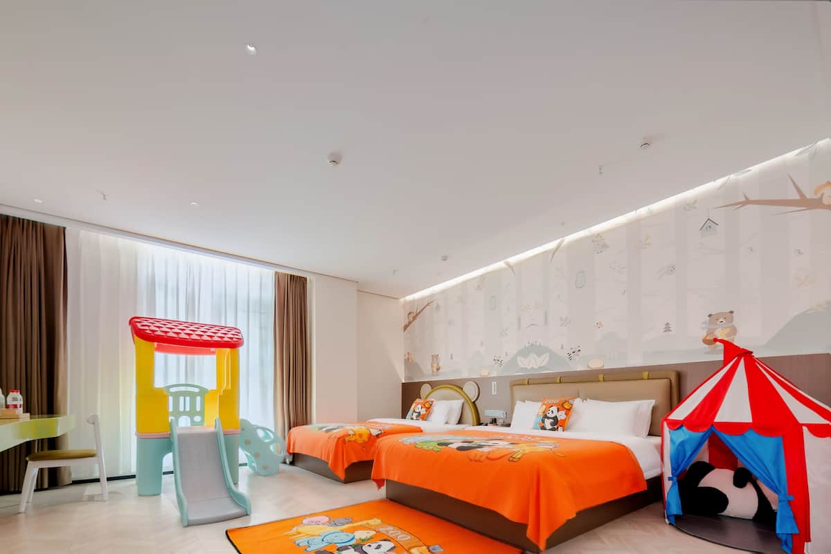 Quarto de hotel com duas camas, um espaço de recreação e uma janela grande.