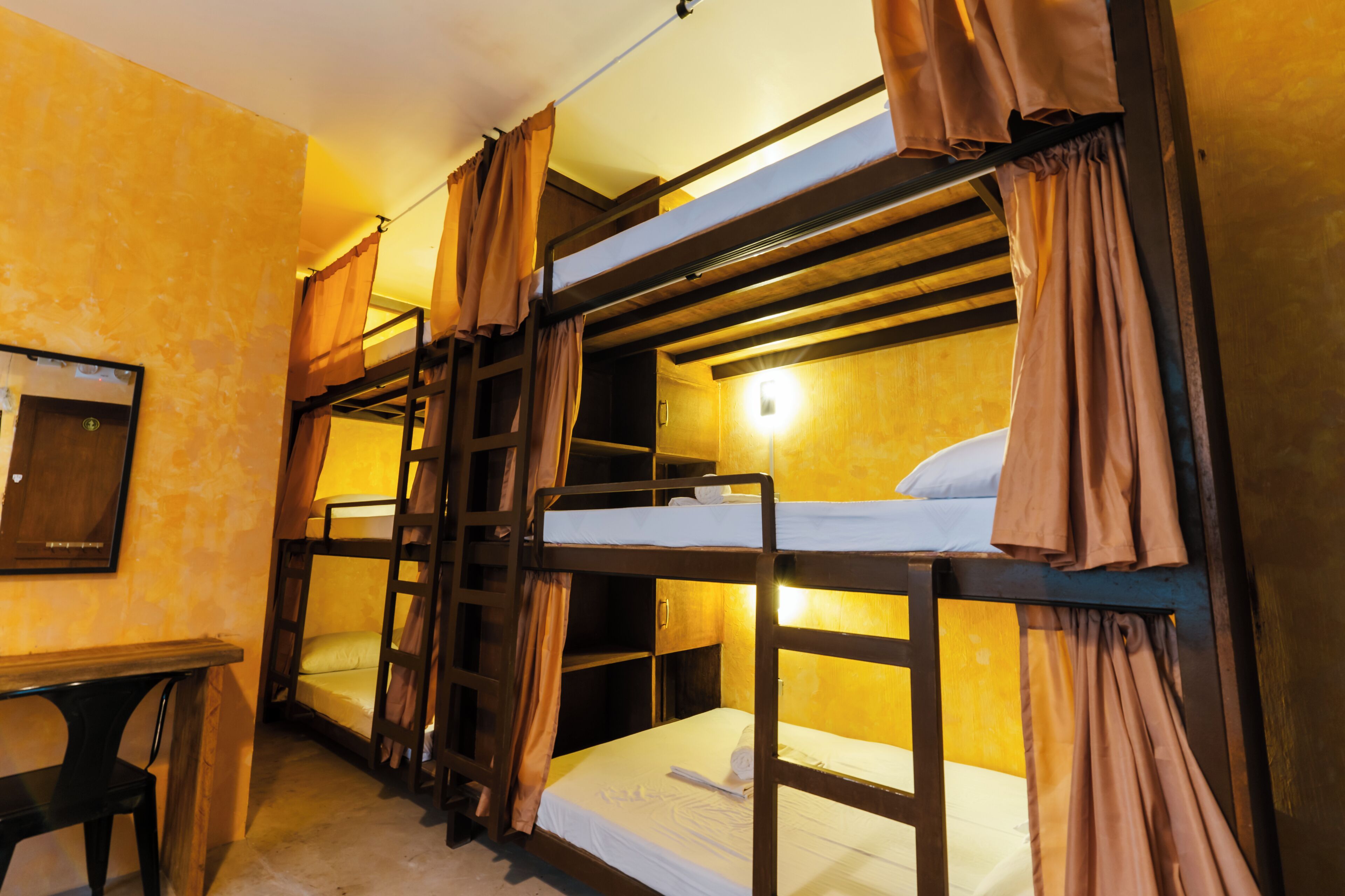 Quarto com beliche, escrivaninha e espelho.