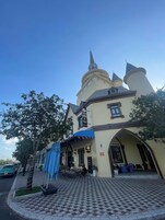 Um edifício com uma torre em formato de pináculo, uma cobertura azul e uma placa indicando uma cafeteria.