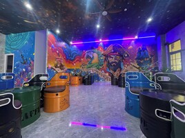 Quarto com mural, ventoinha no teto e área de estar com tambores.