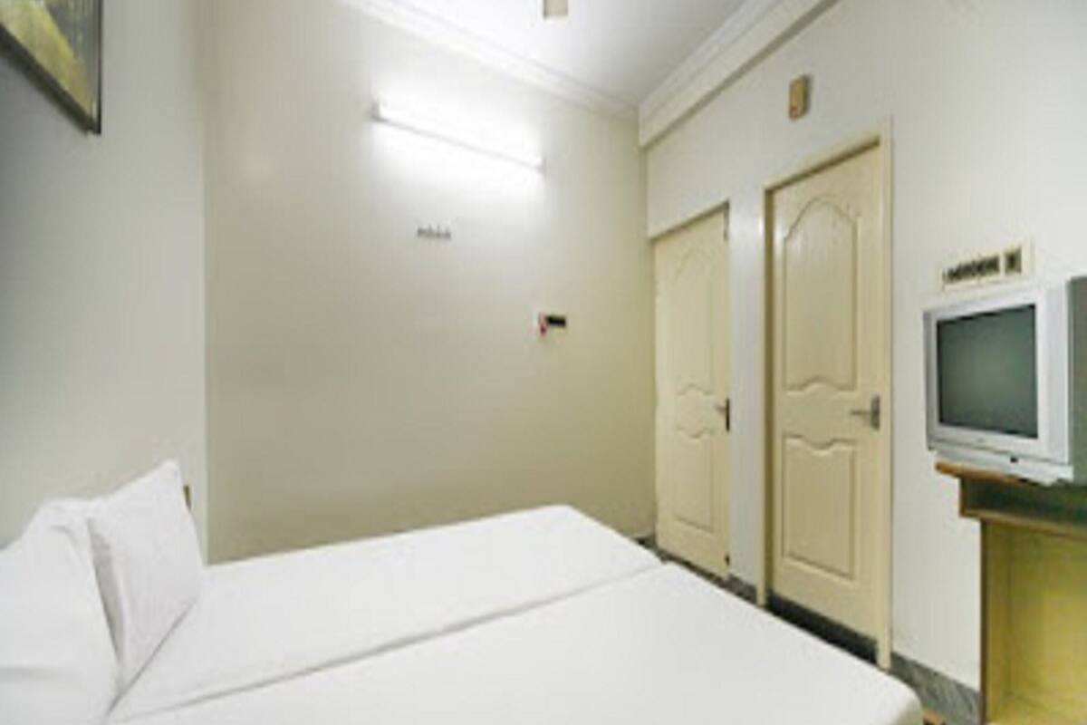 Quarto de hotel com uma cama, uma televisão e duas portas.