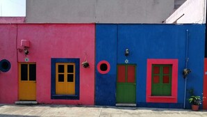 Um edifício com três portas, cada uma pintada de uma cor diferente: amarelo, verde e vermelho.