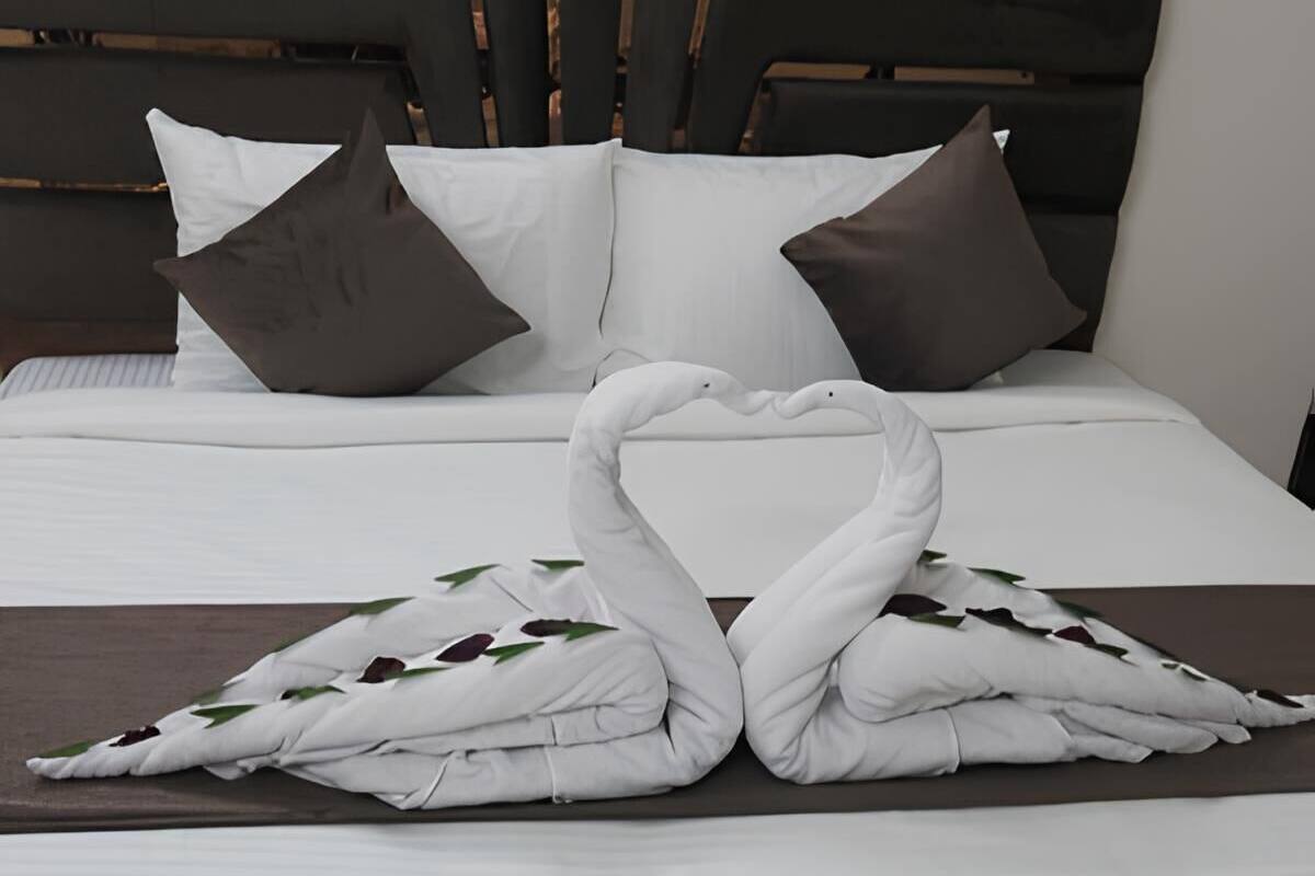 Uma cama bem arrumada, com cabeceira, almofadas e um arranjo de toalha em formato de cisne.