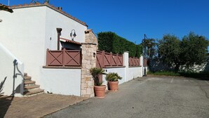 Um edifício branco com parede de pedra, persianas castanhas e plantas em vasos.