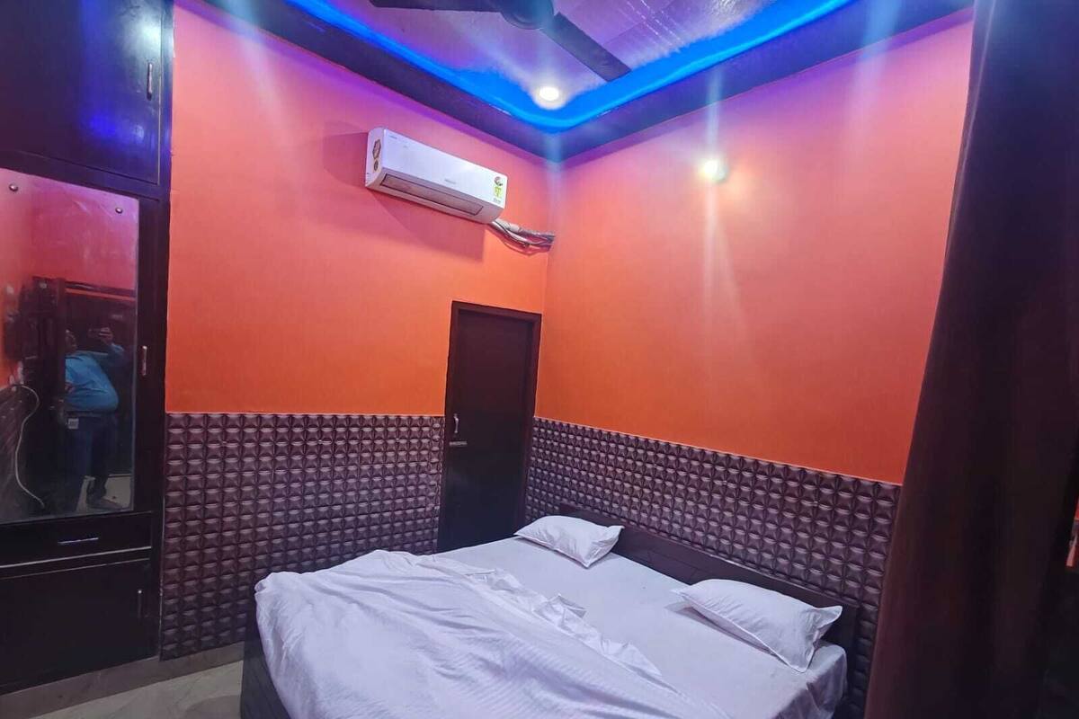 Quarto com ar condicionado, cama com roupa de cama branca e uma porta.
