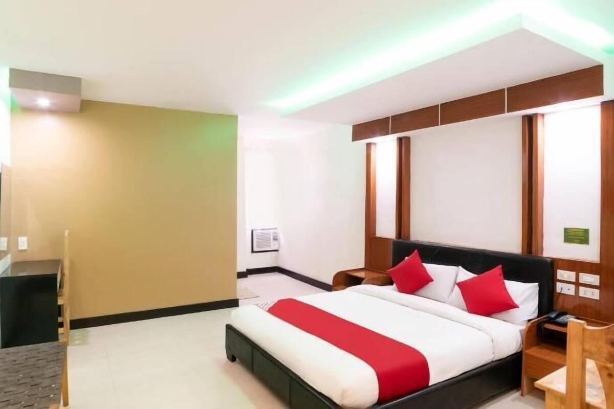 Quarto de hotel com cama, mesa de cabeceira, cadeira e televisão de tela plana na parede.