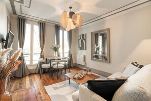 Uma sala de estar moderna com sofá, uma mesa de jantar com cadeiras, televisão e um espelho grande.
