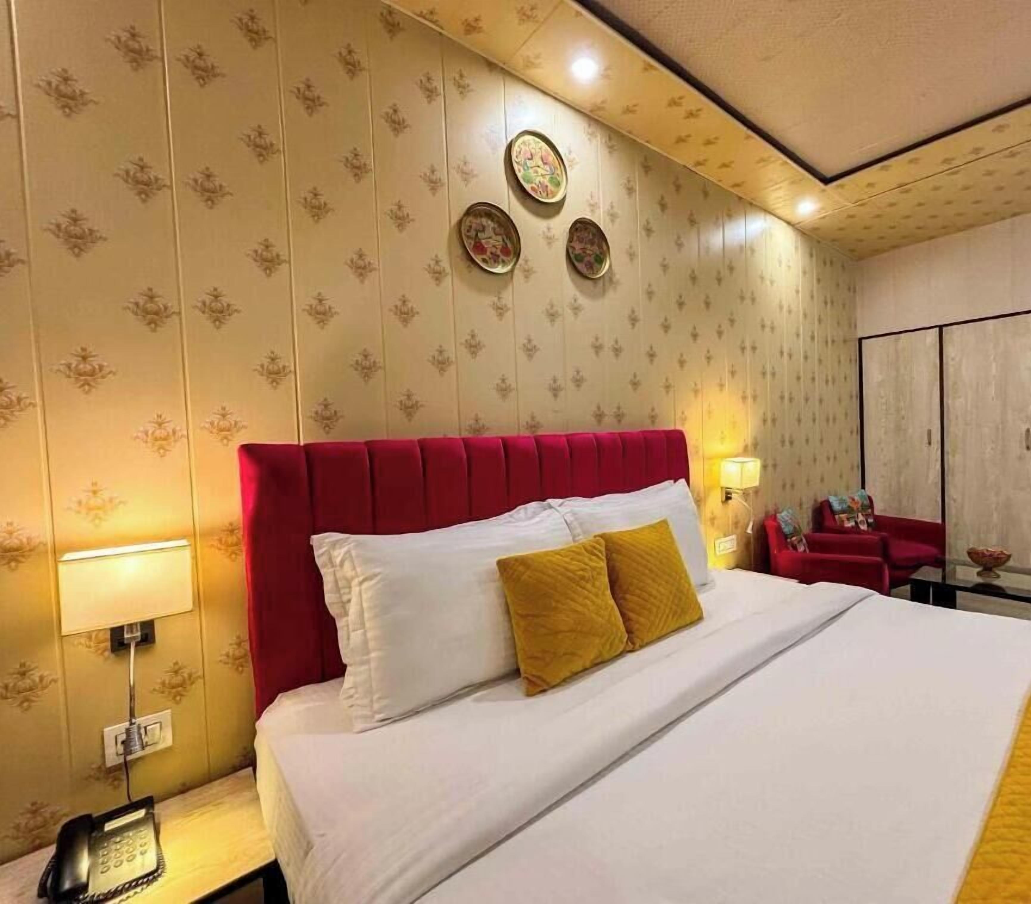 Quarto de hotel com uma cama grande, cabeceira vermelha e telefone fixado na parede.