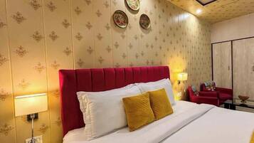 Quarto de hotel com uma cama grande, cabeceira vermelha e telefone fixado na parede.