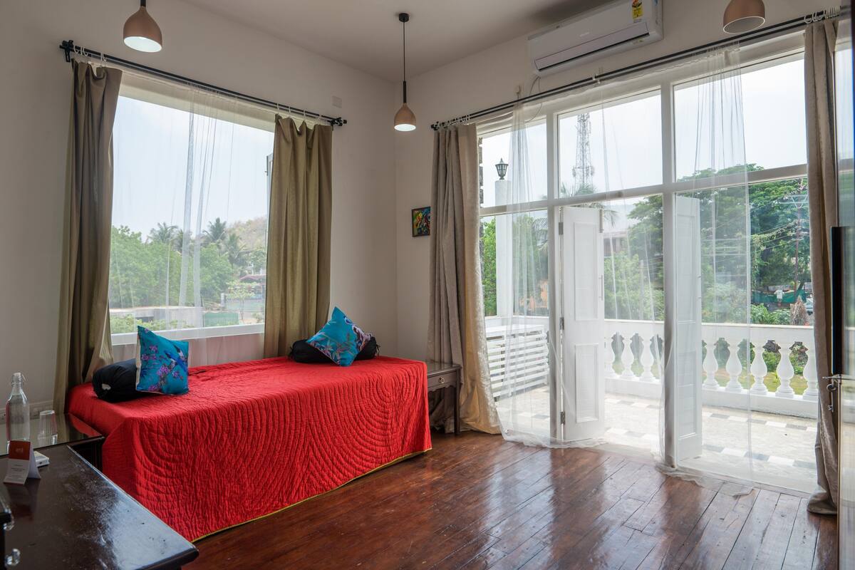 Um quarto com cama, uma mesa e vista através de janelas amplas.