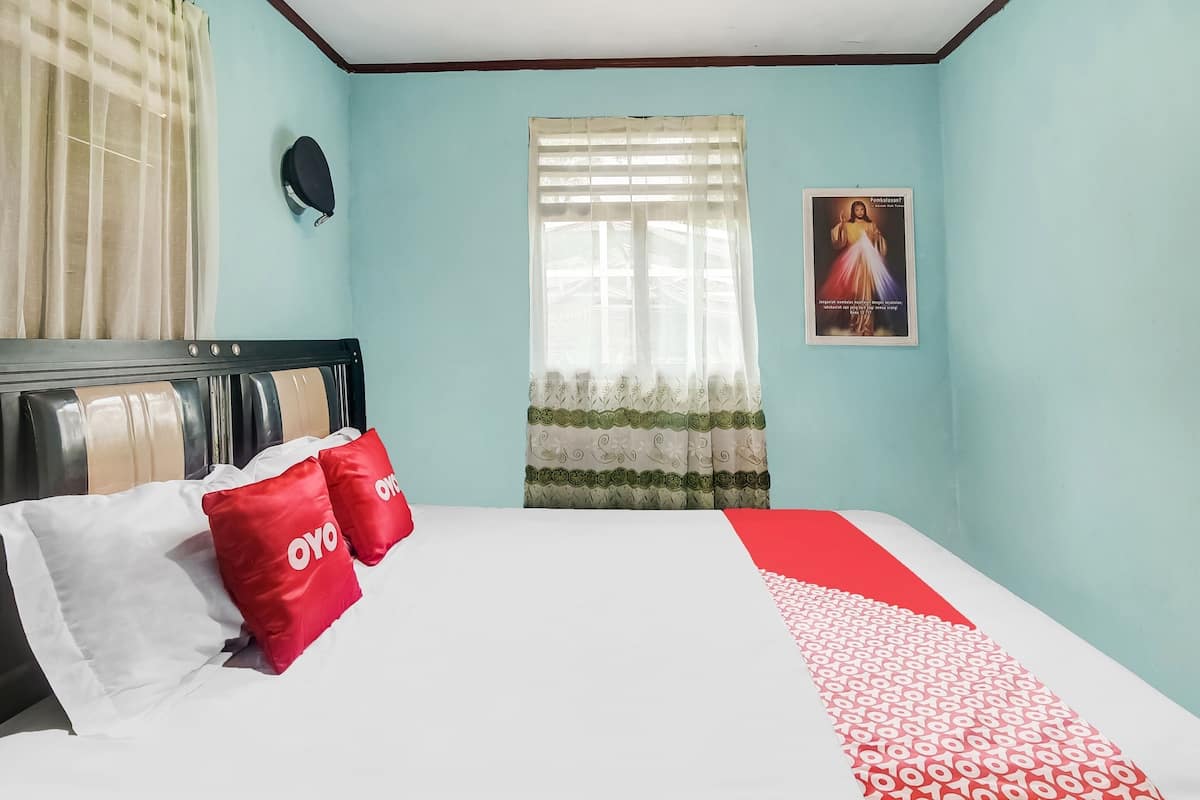 Quarto com cama, janela com cortinas, relógio fixado na parede e quadro emoldurado.