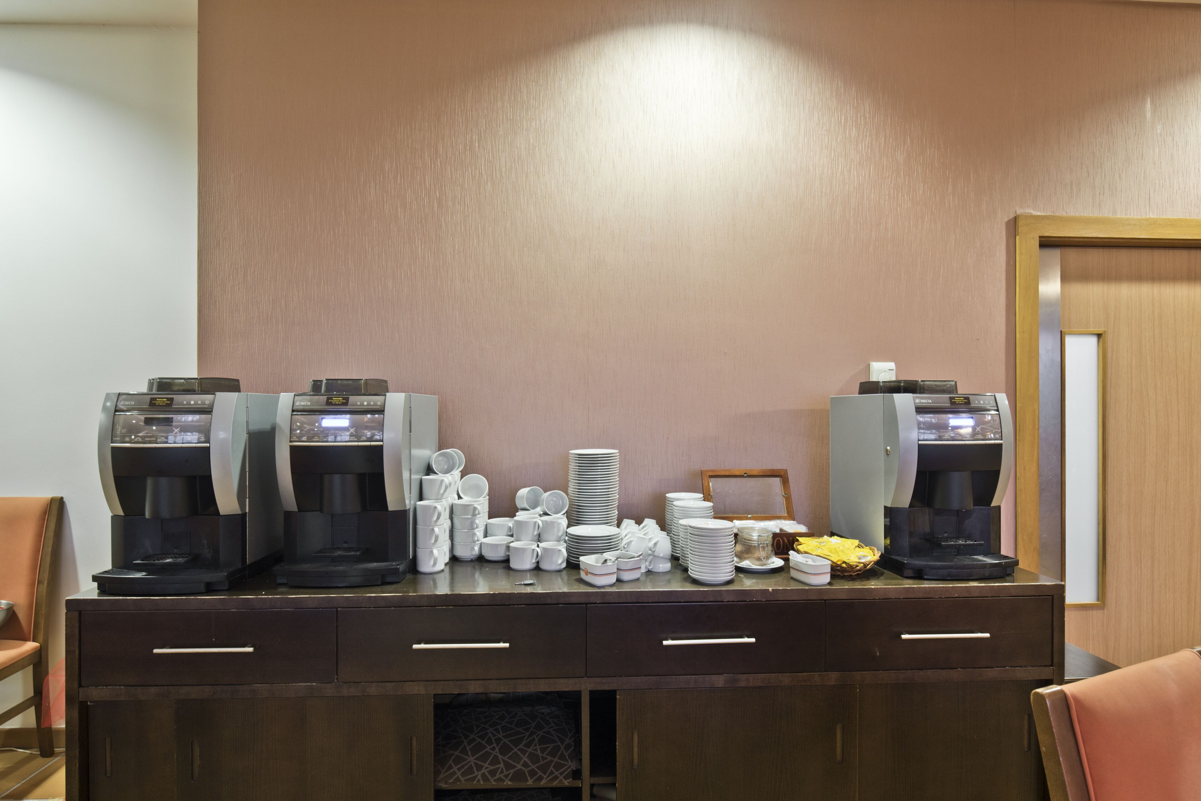 Uma estação de café com várias máquinas de café e uma variedade de xícaras e pratos.