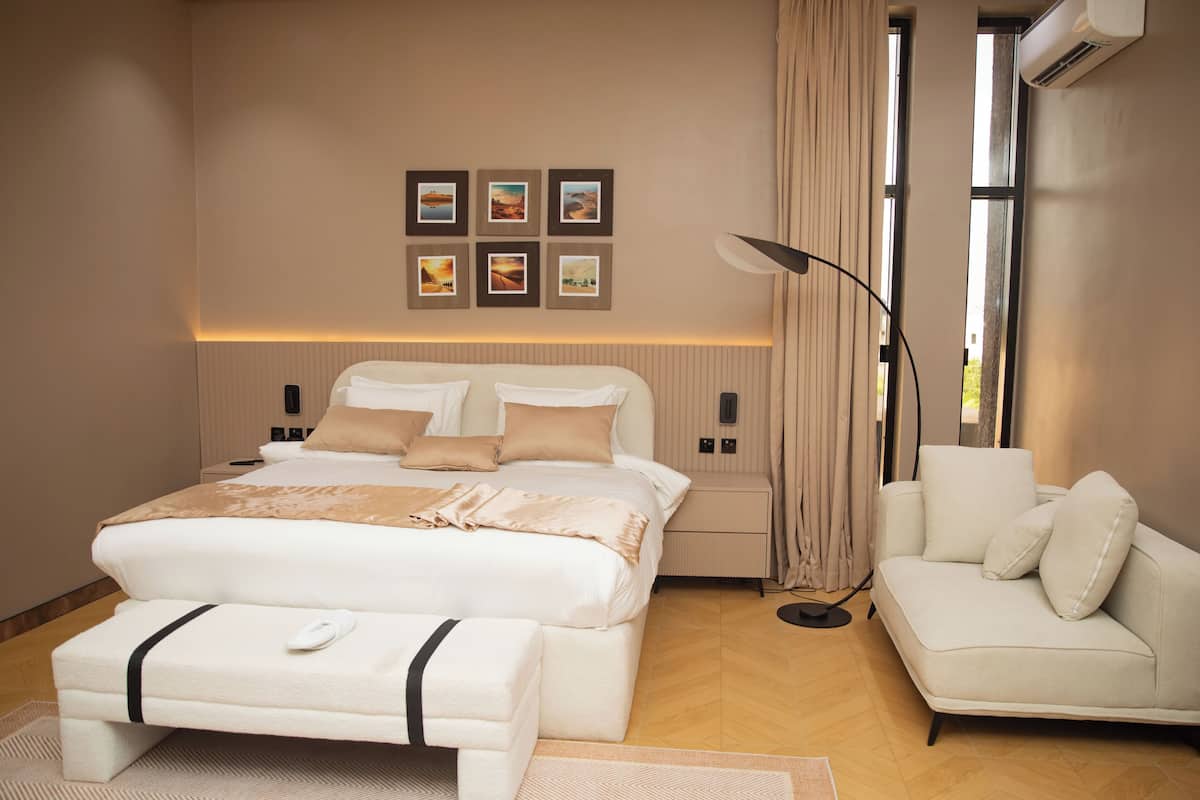 Um quarto moderno com uma cama grande, mesas de cabeceira, um sofá e um ar condicionado fixado na parede.
