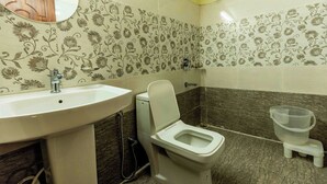 Casa de banho com sanita, lavatório e chuveiro.
