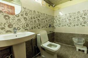 Casa de banho com sanita, lavatório e chuveiro.