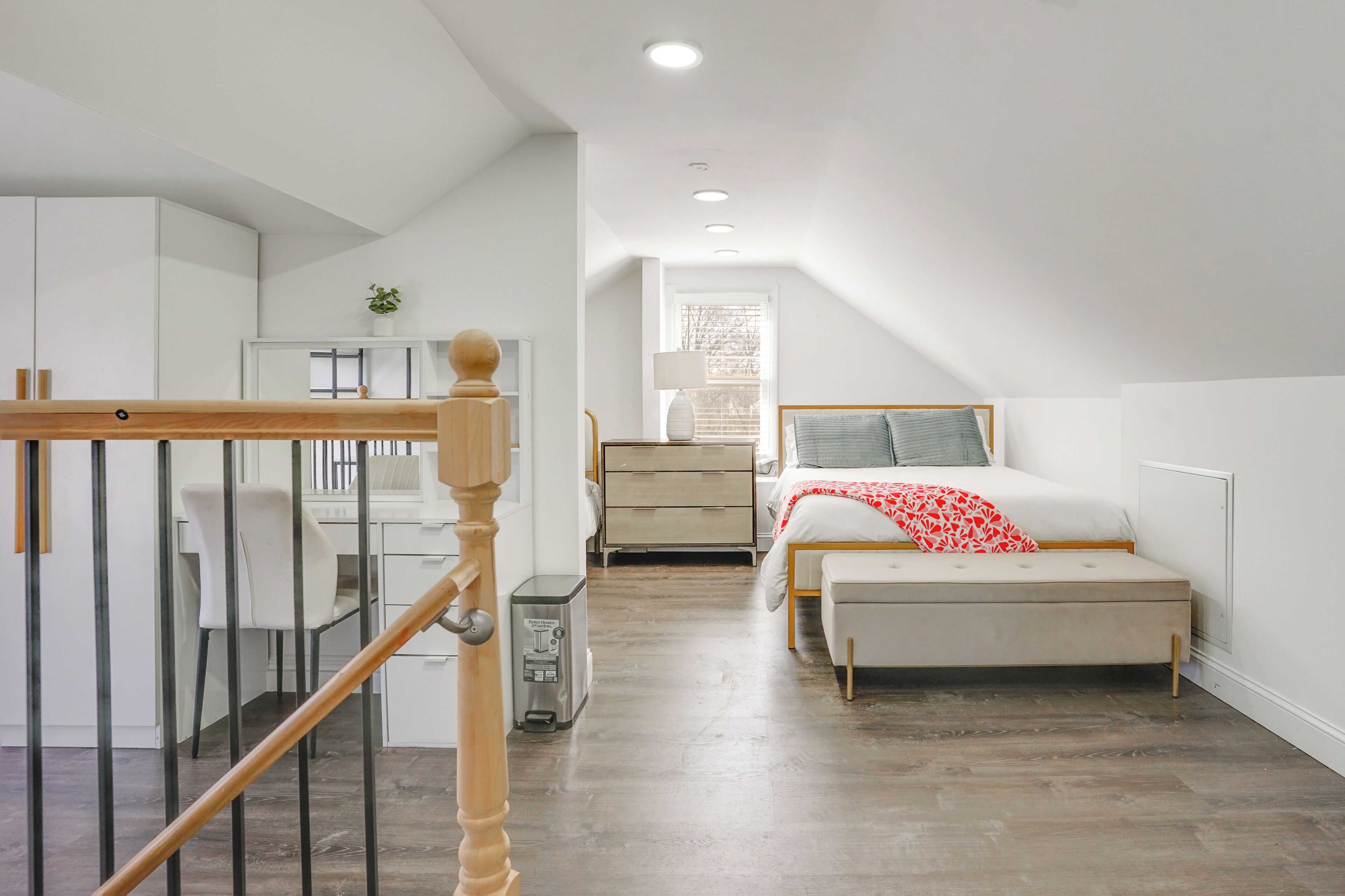 Quarto com cama, mesa de cabeceira, abajur e vista para o exterior.