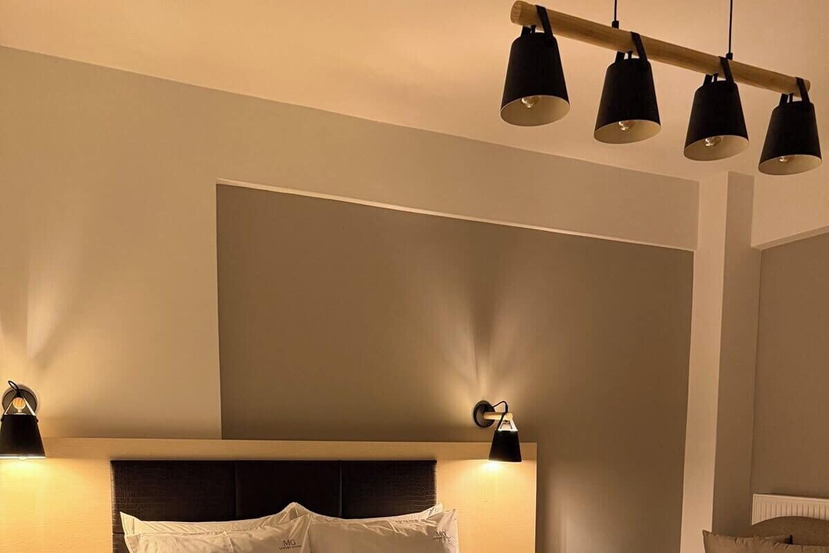 Quarto moderno com uma cama grande, luminárias de cabeceira e cabeceira.