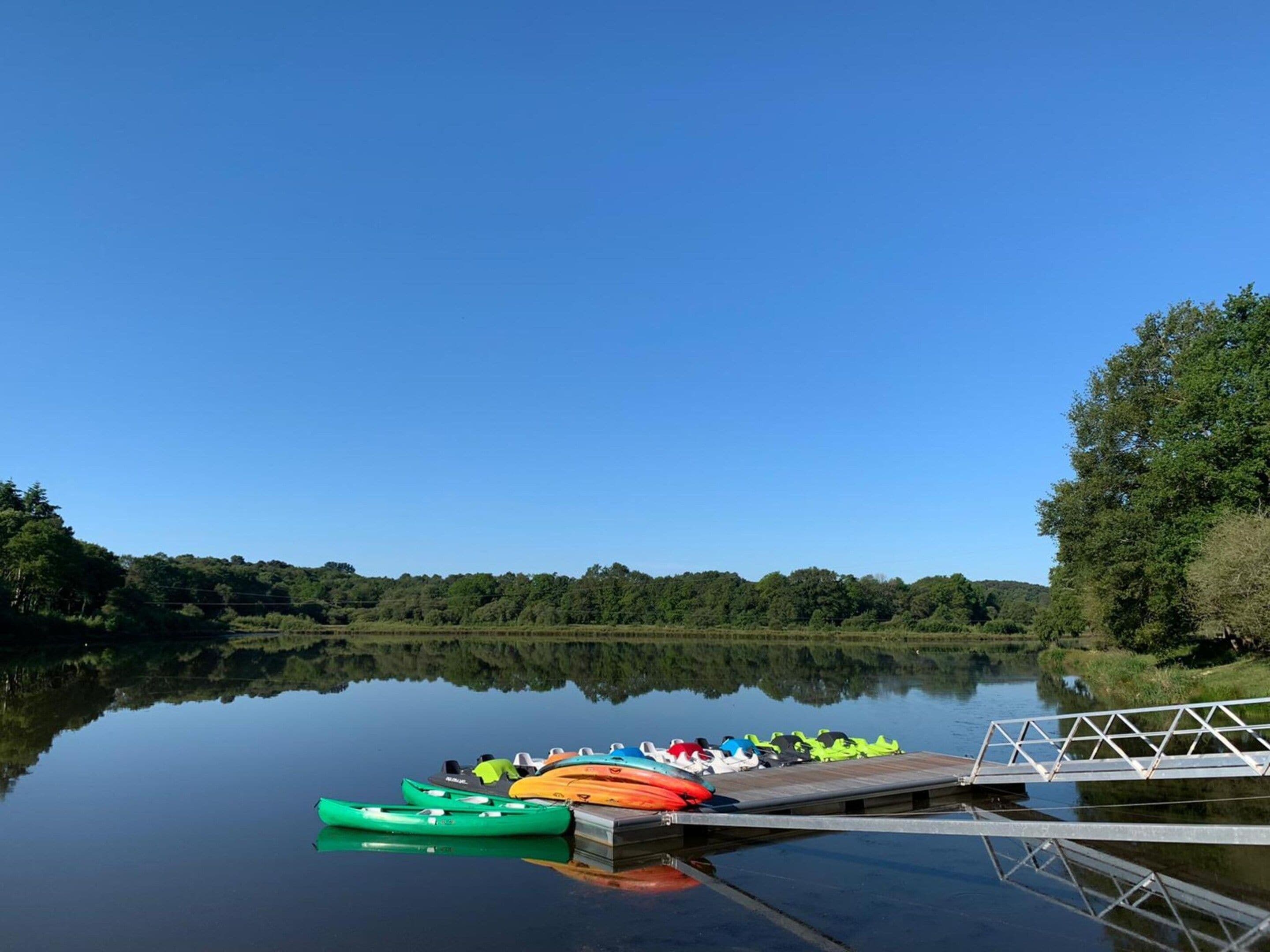 Um lago tranquilo com um píer e caiaques.