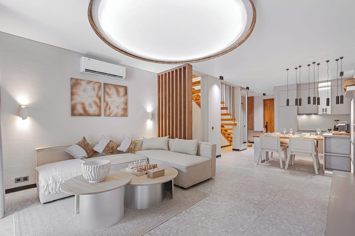 Uma sala de estar moderna com um sofá seccional, uma mesa de centro e uma área de jantar com mesa e cadeiras.