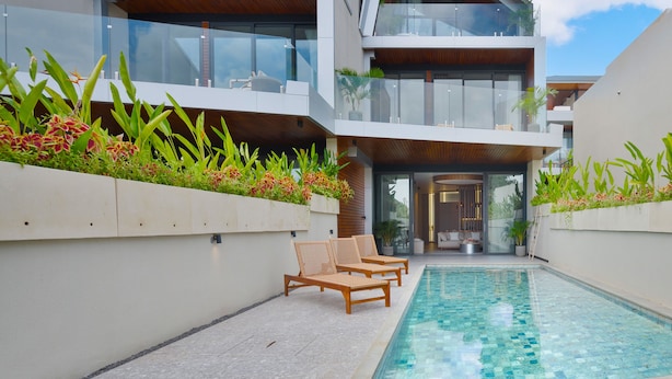 Um edifício moderno com piscina, espreguiçadeiras e um jardim bem cuidado.