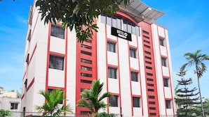 Um hotel de vários andares com um letreiro chamativo 'HOTEL', fachada em vermelho e branco, várias janelas e telhado plano.