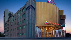 Um hotel moderno com fachada curva marcante, entrada ampla e sinalização com 'Ramada Encore by Wyndham'.